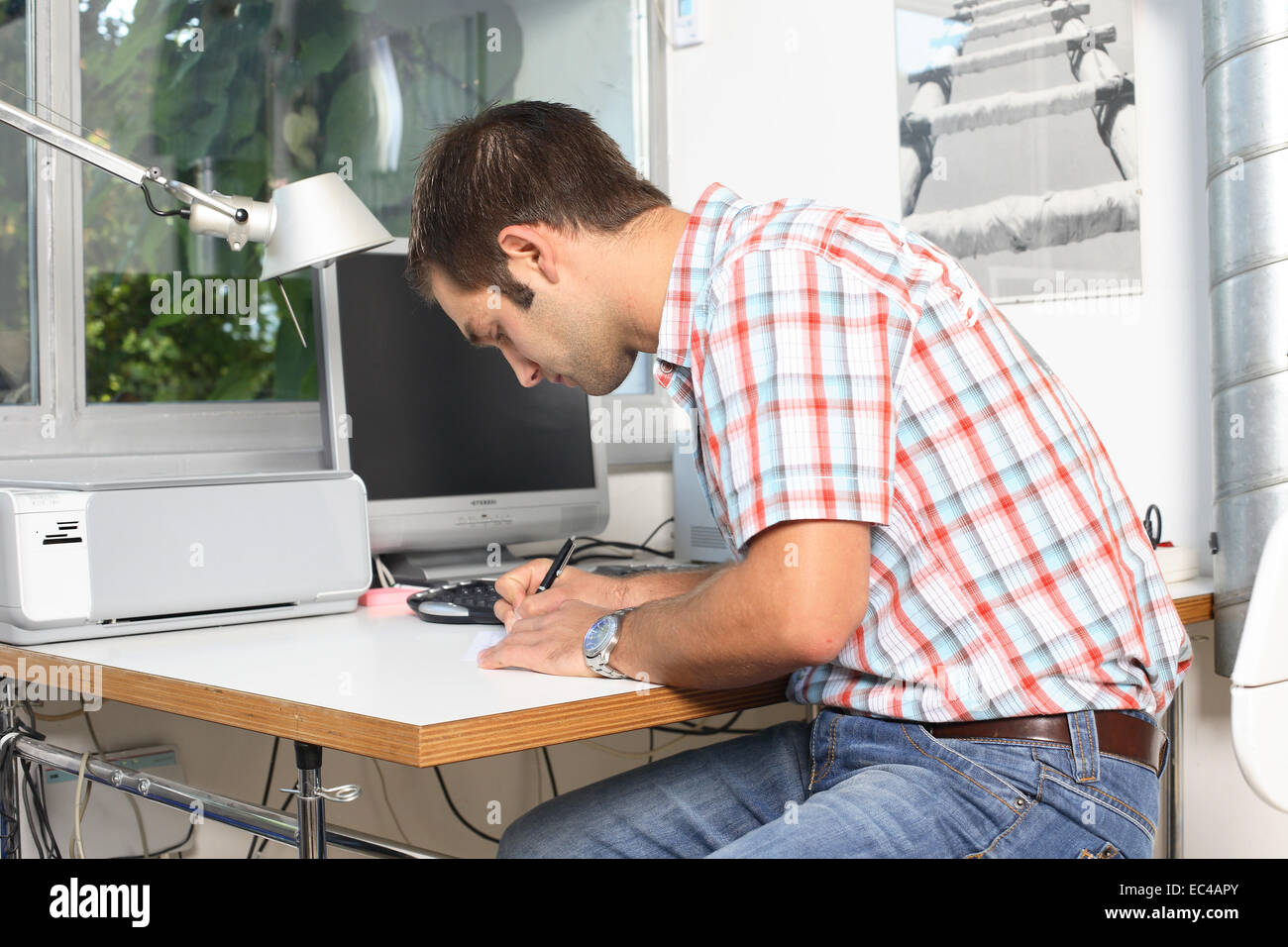 Man Sitting Writing at a Desk Stock Photo - Alamy