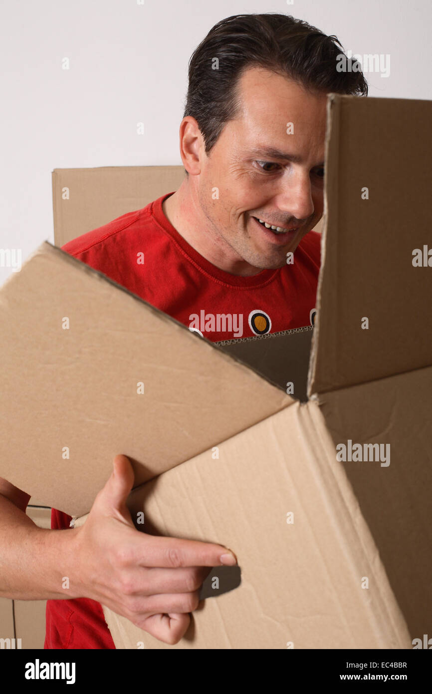 Man Moving Home, bearing, looking in moving box Stock Photo - Alamy