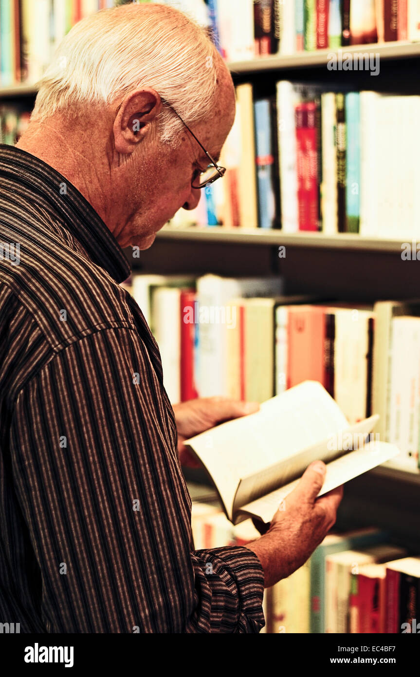 A old man reads a book in a library Stock Photo - Alamy
