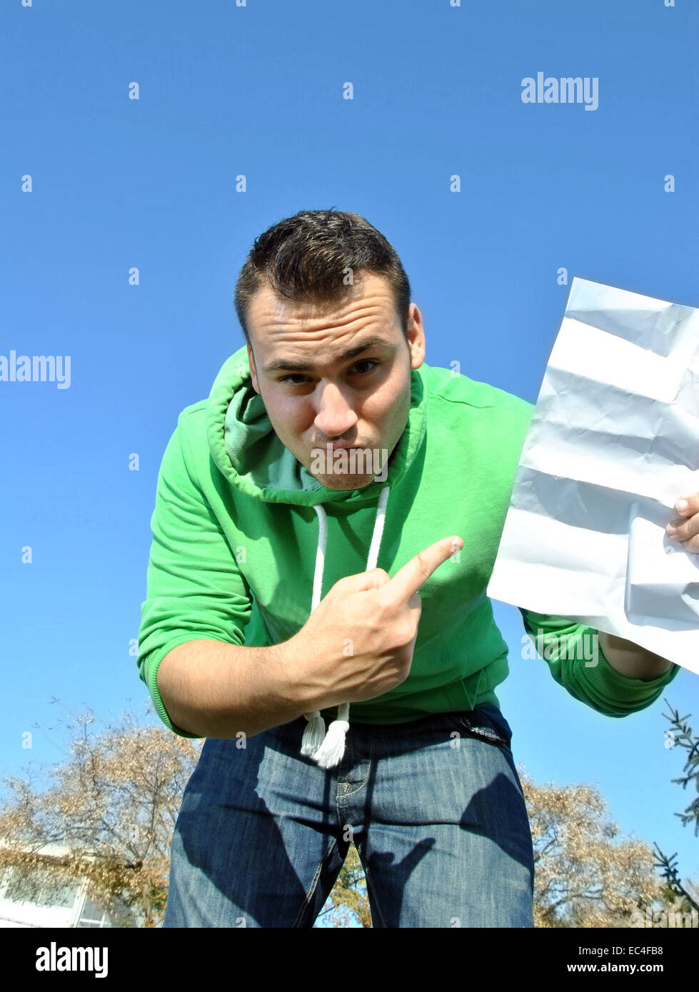 Young man showing a paper with mad face Stock Photo - Alamy