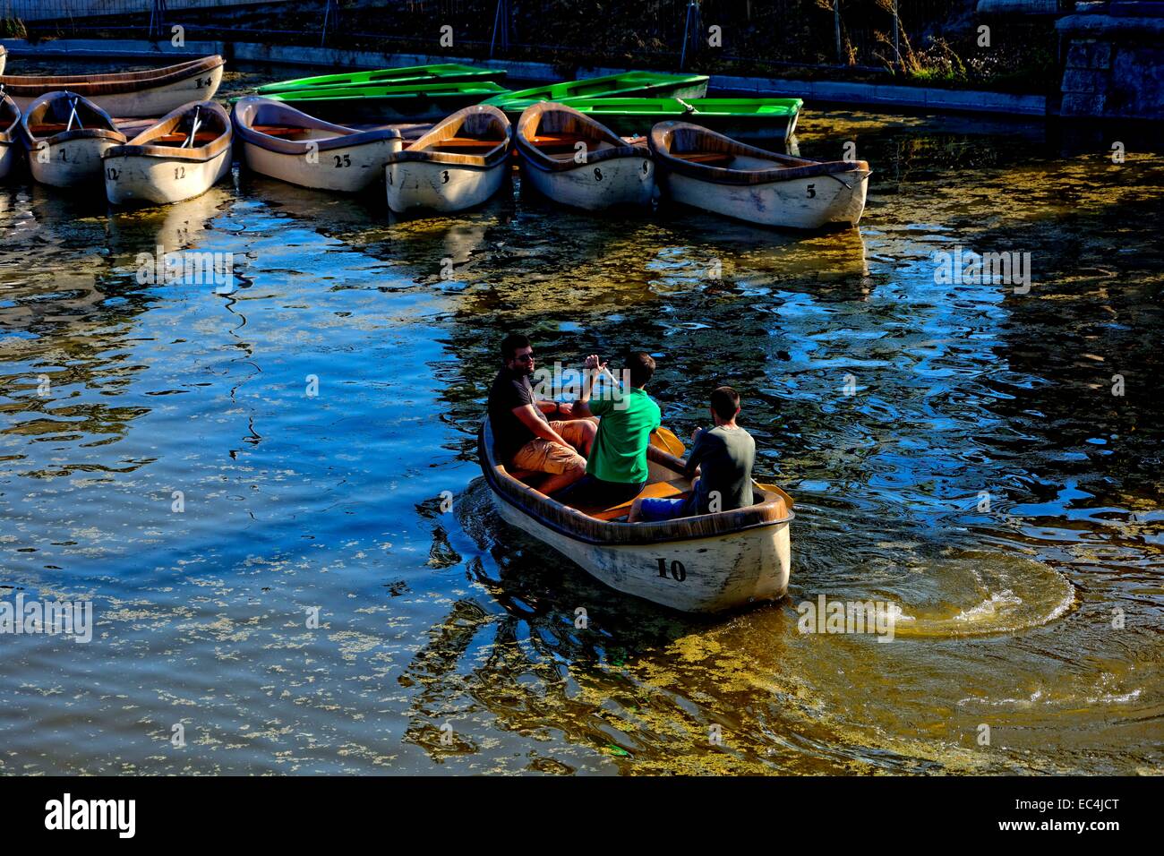 Canadian green rowing boats at the pier, three men paddling and leisure ...