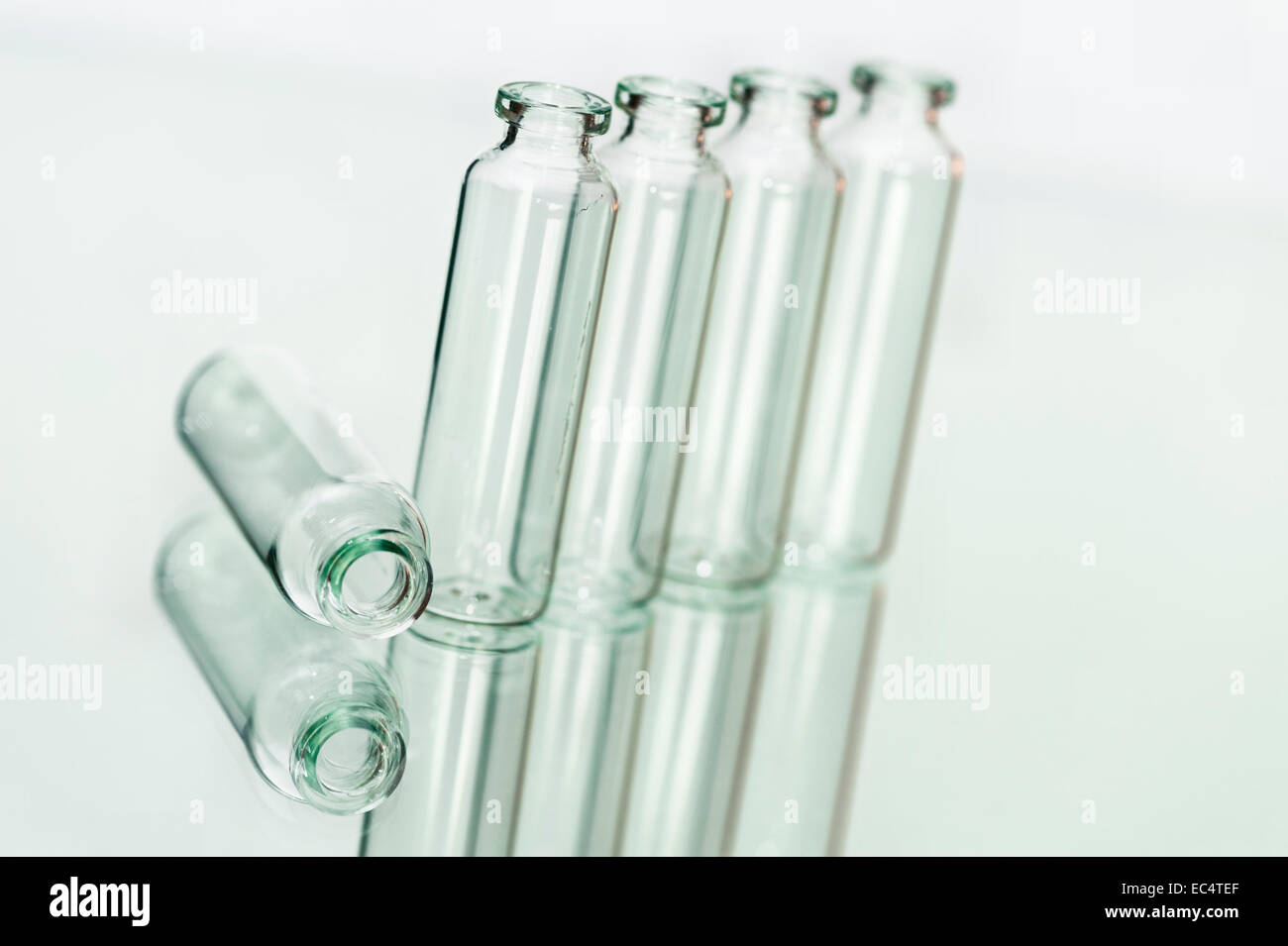 5 small glass tubes and are placed on a mirrored table top Stock Photo ...