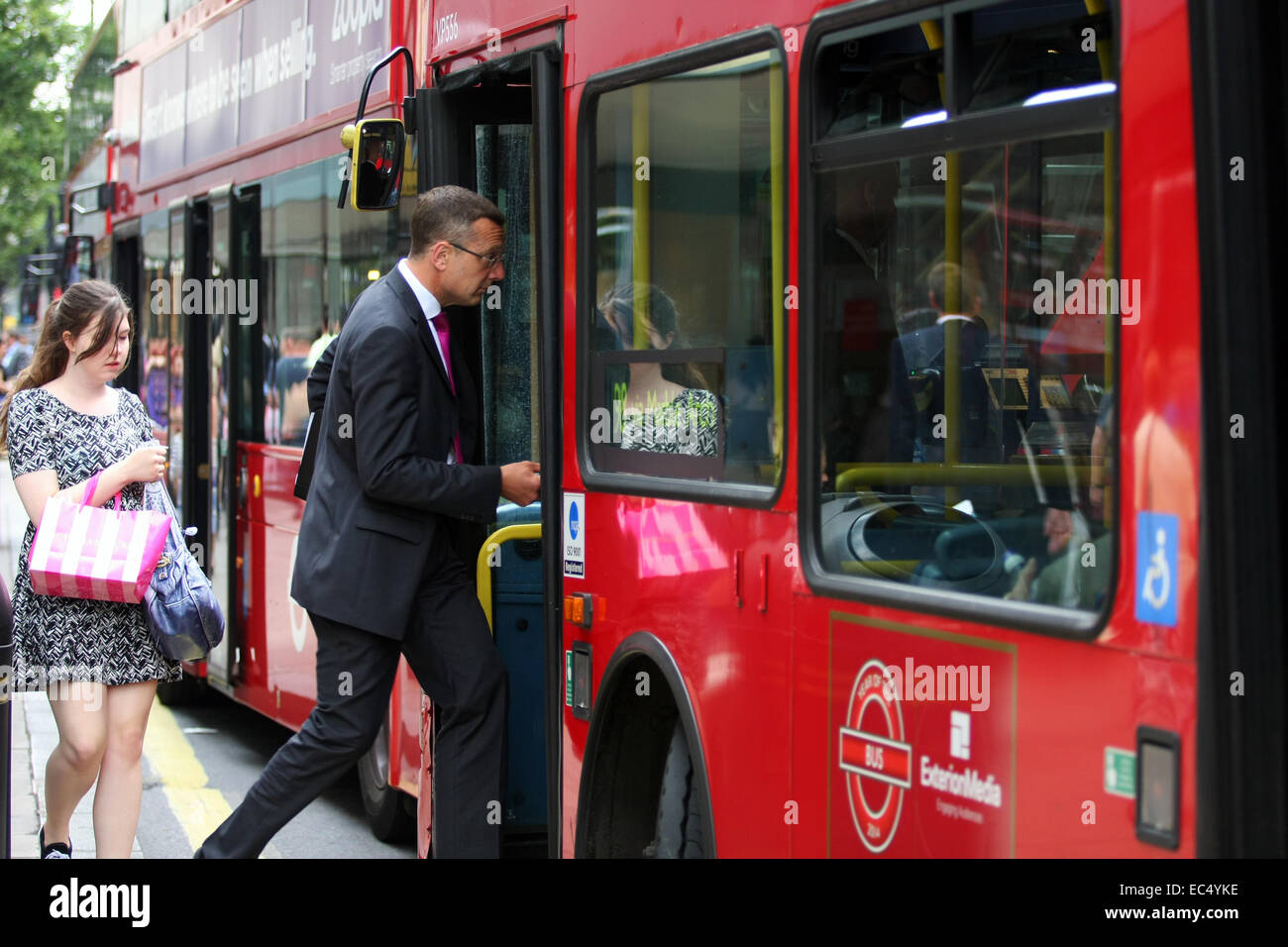 People boarding a red London bus at a bus stop in London Stock Photo ...