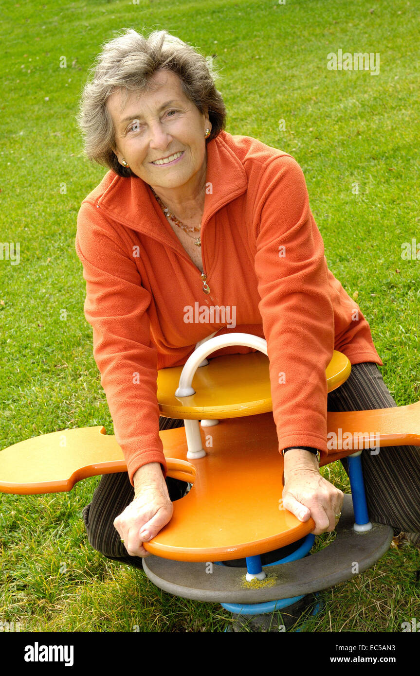 Happy senior woman on a playground toy Stock Photo - Alamy