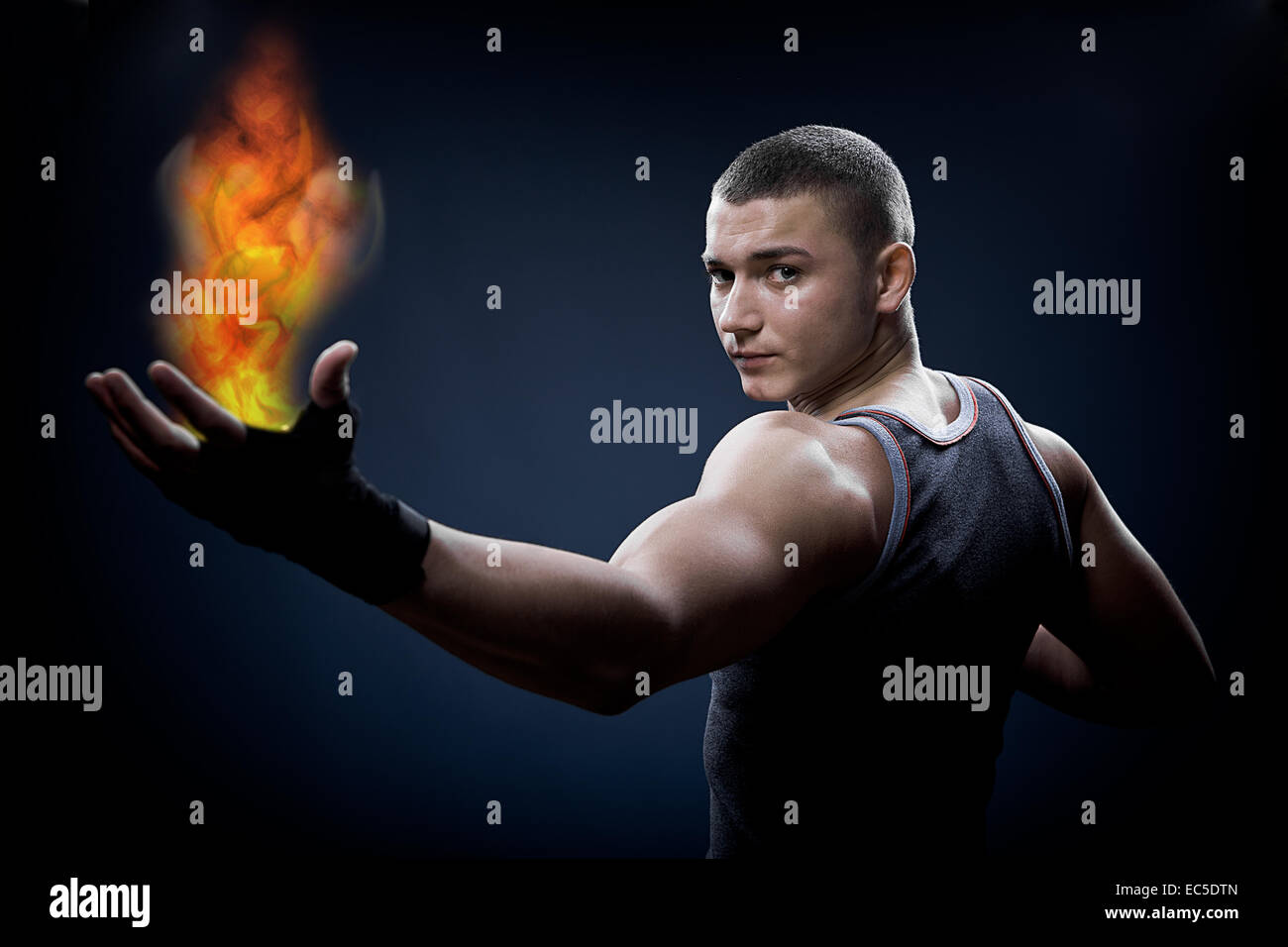 portrait of a young boxer with fire in the hand in front of dark ...
