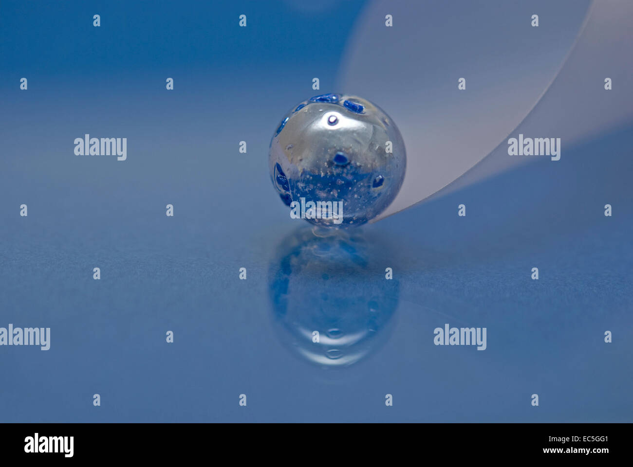 glass marble which is reflected on a blue background Stock Photo - Alamy
