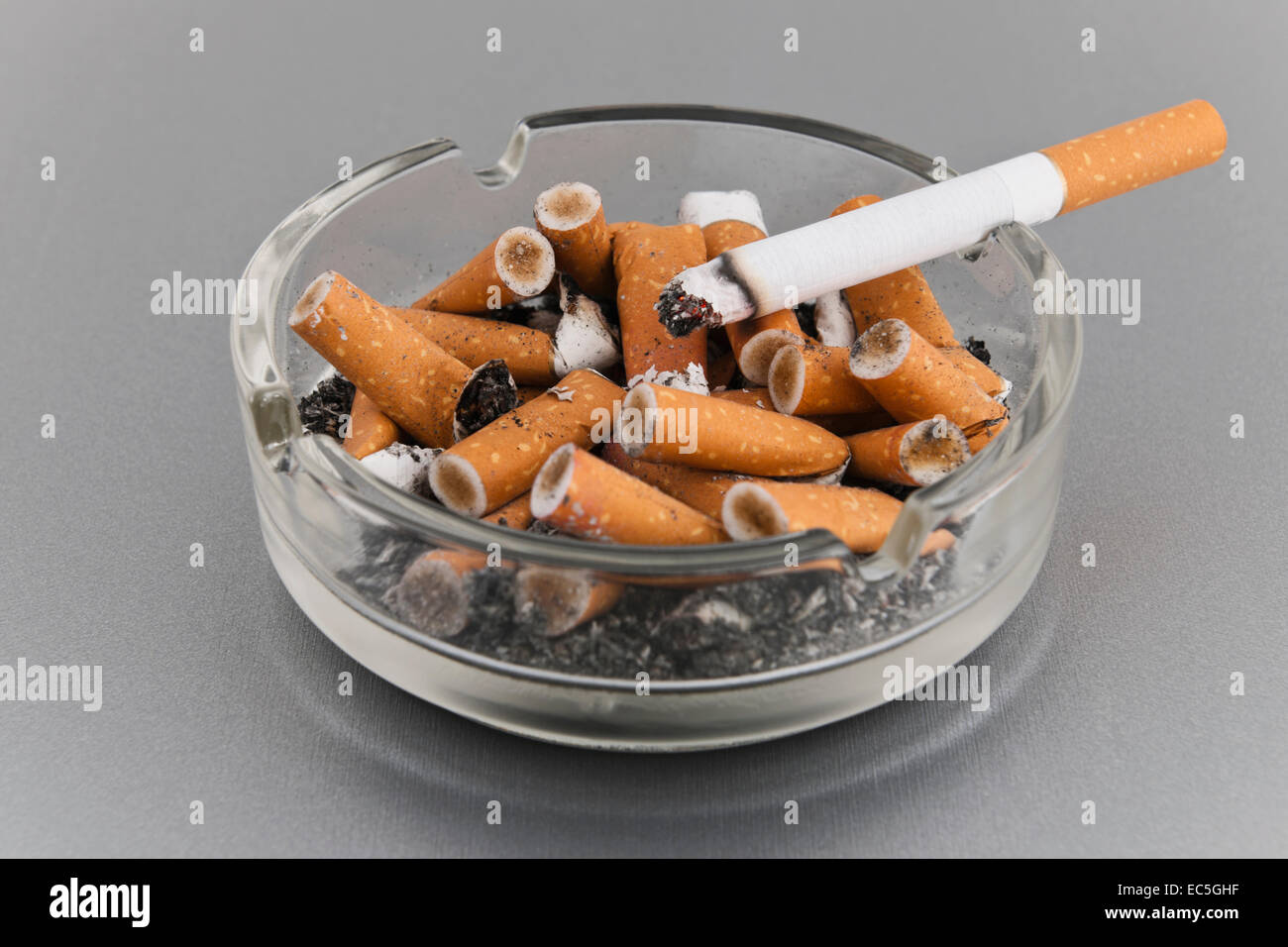 full ashtray and a glowing cigarette Stock Photo - Alamy