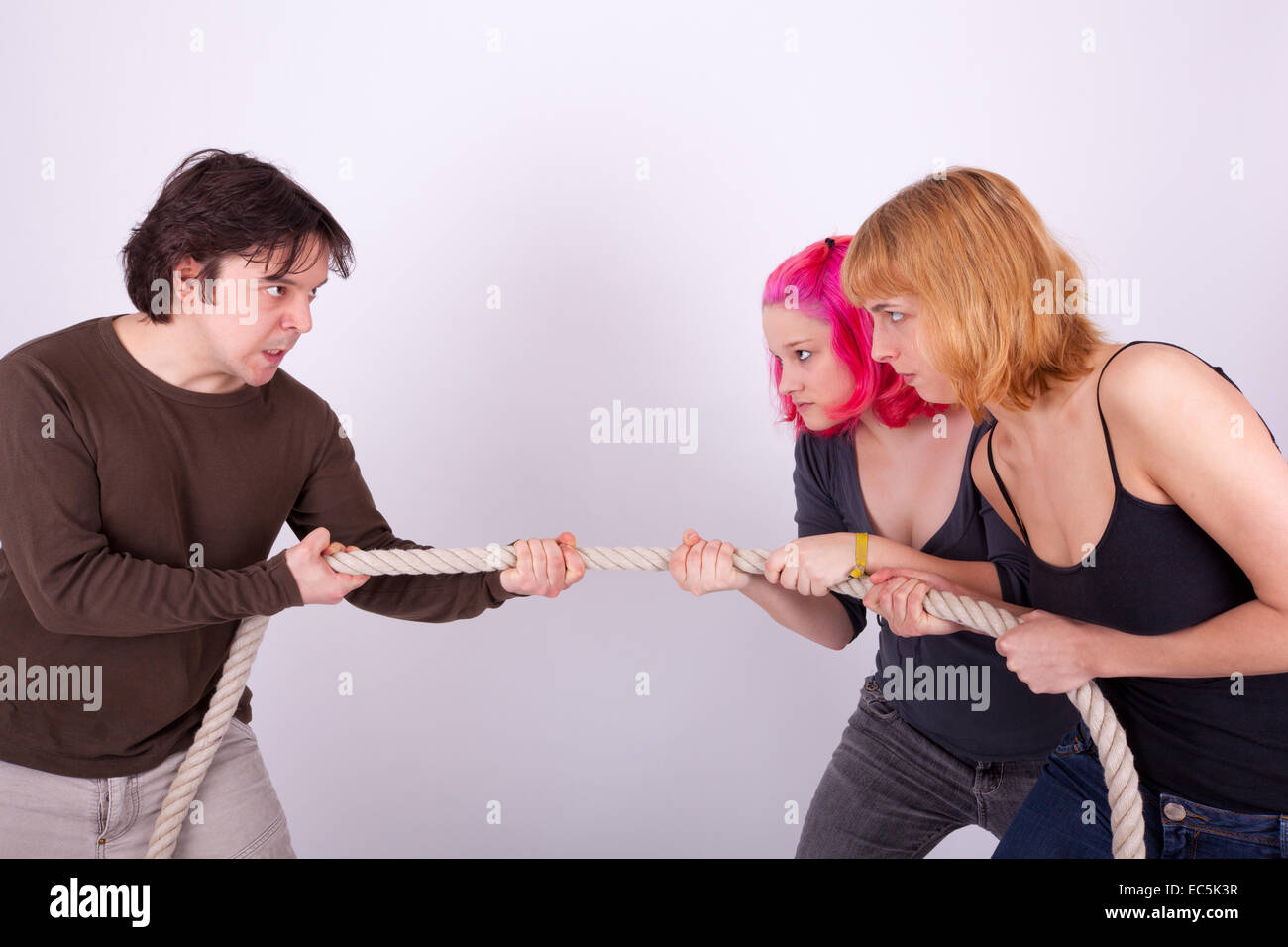 Two women and a man are pulling a rope Stock Photo - Alamy