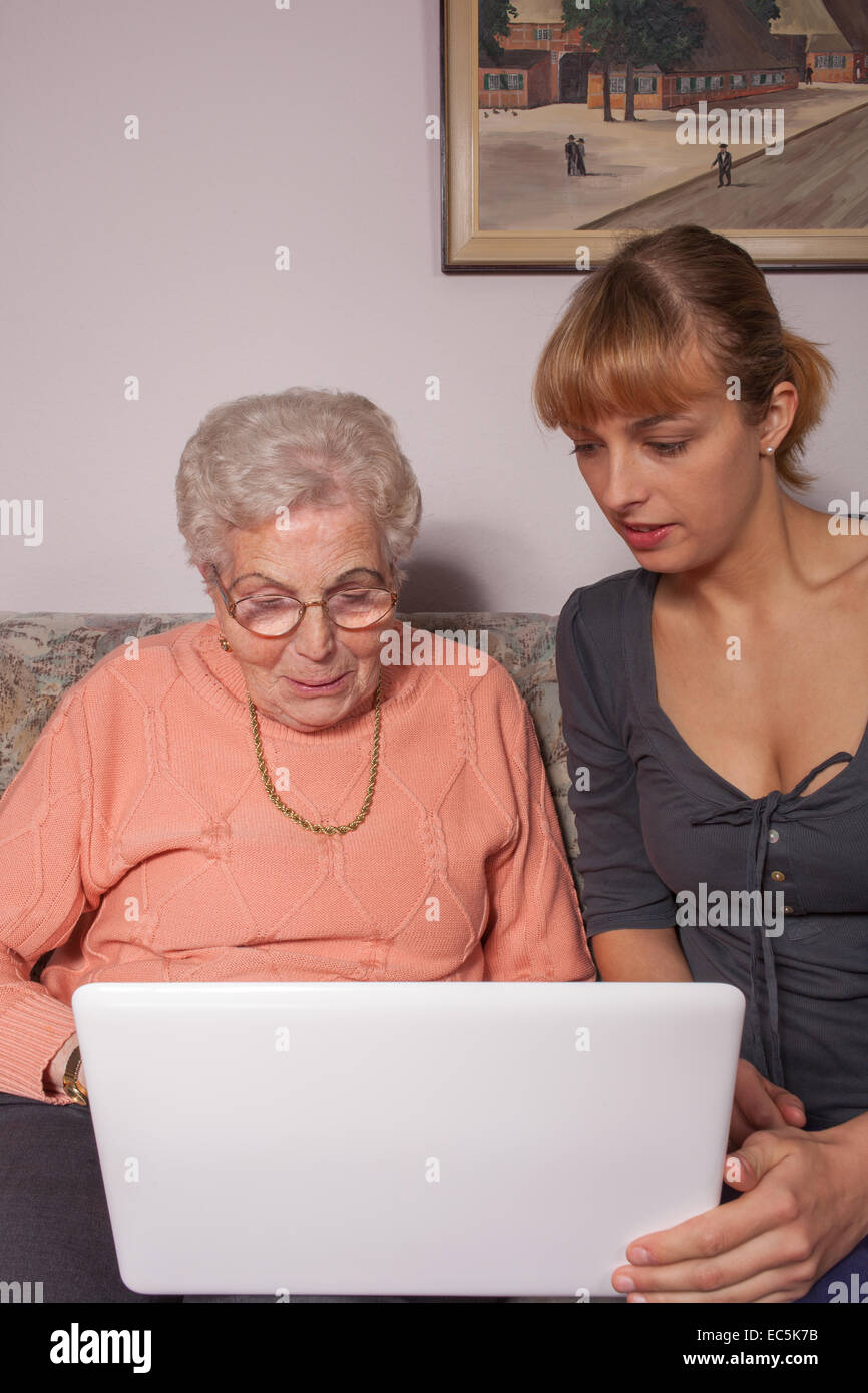 An old woman is a laptop explained by her granddaughter Stock Photo - Alamy