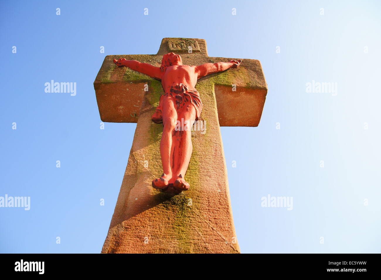 Stone path cross with red Christ Stock Photo - Alamy