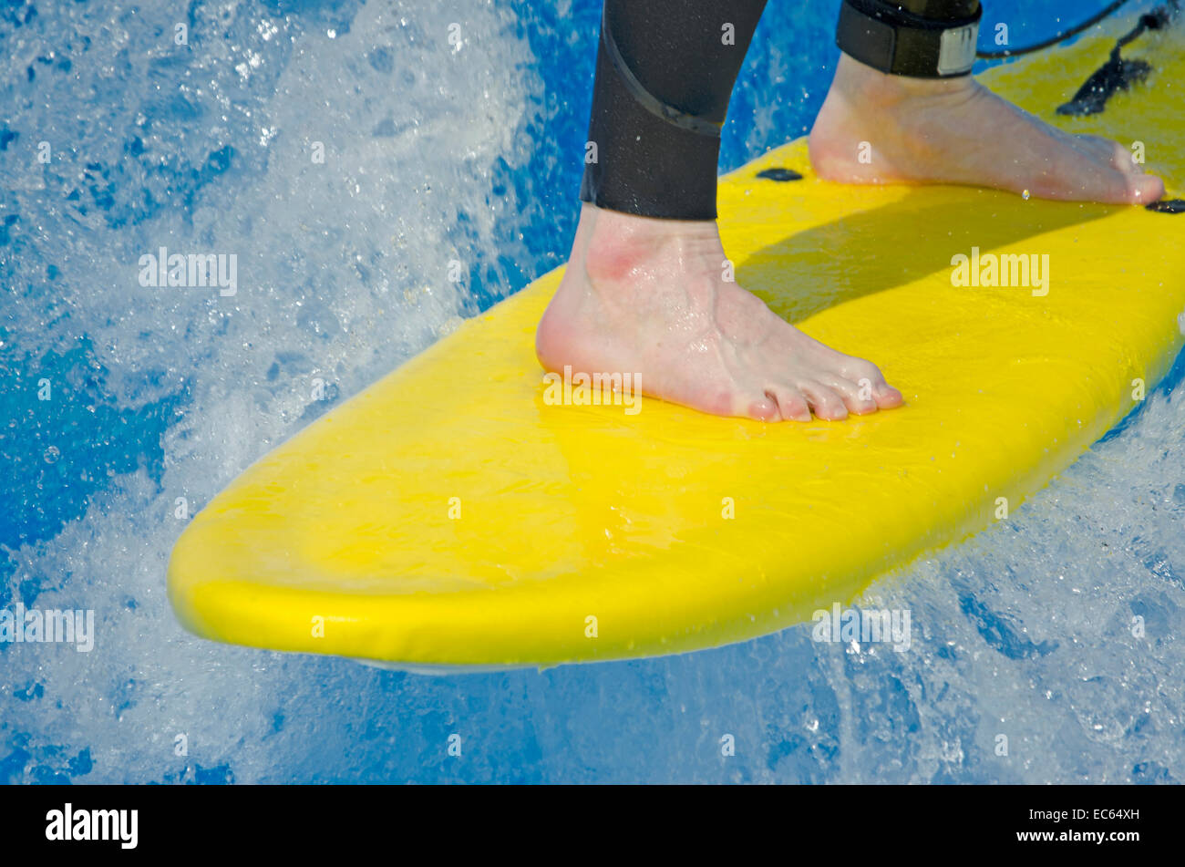 Surfer standing on a yellow surfboard Stock Photo - Alamy
