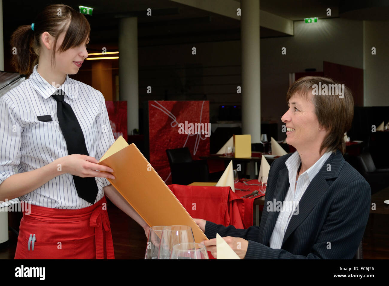 Waitress presents menu Stock Photo - Alamy