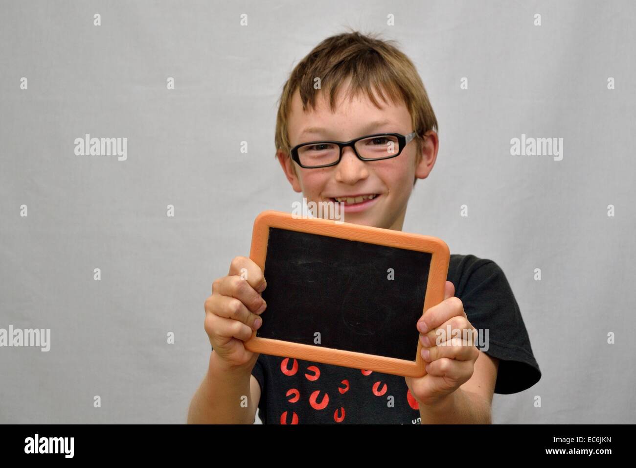 Boy holding small blackboard in his hand and laughs Stock Photo - Alamy