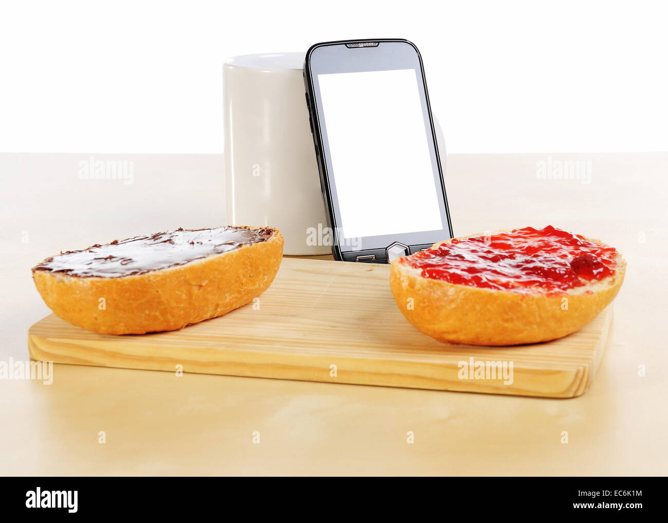 bread rolls with hazelnut cream and marmelade, mobile phone an coffee ...