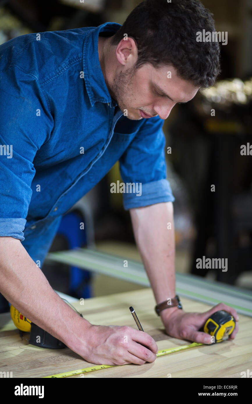 Photograph of carpenter measuring a piece of bespoke furniture in his ...