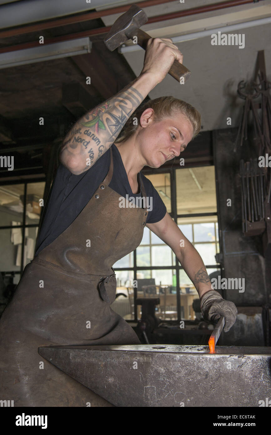 female blacksmith working at ambos with hammer on redhot steel Stock ...