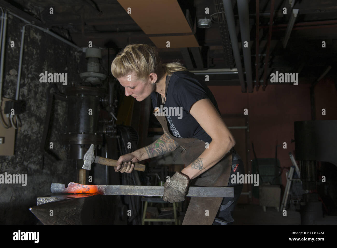 female blacksmith working at ambos with hammer on redhot steel Stock ...