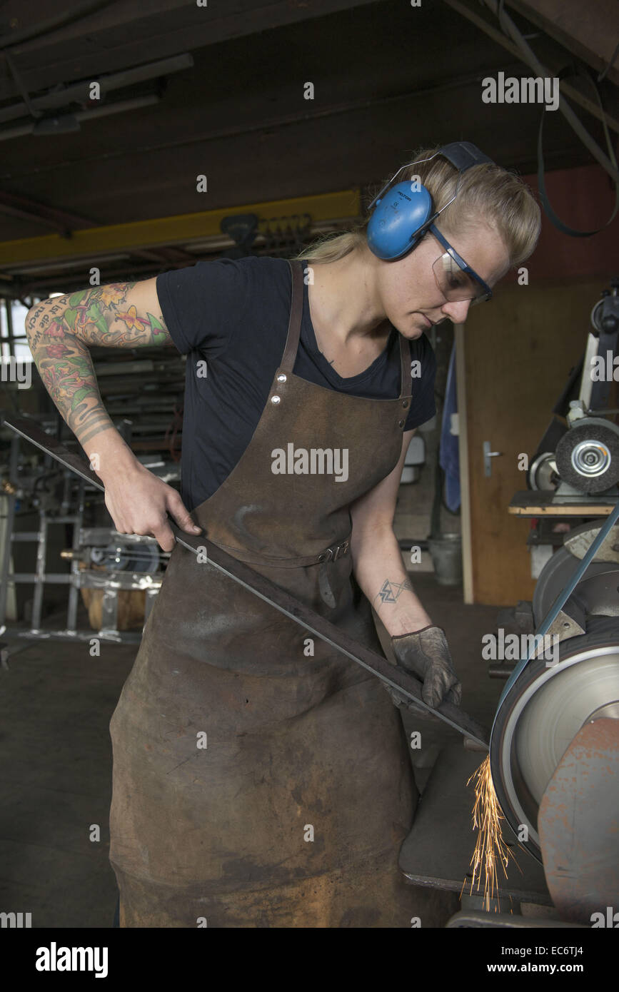 young female blacksmith works at belt grinder Stock Photo - Alamy