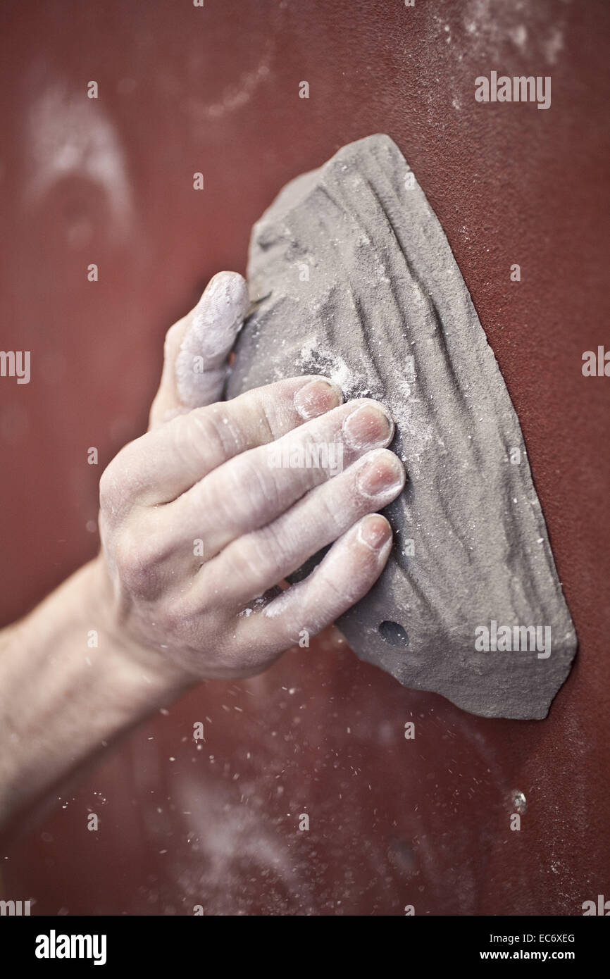 Climbers hand on a grip in a climbing hall, with chalk dust and red ...