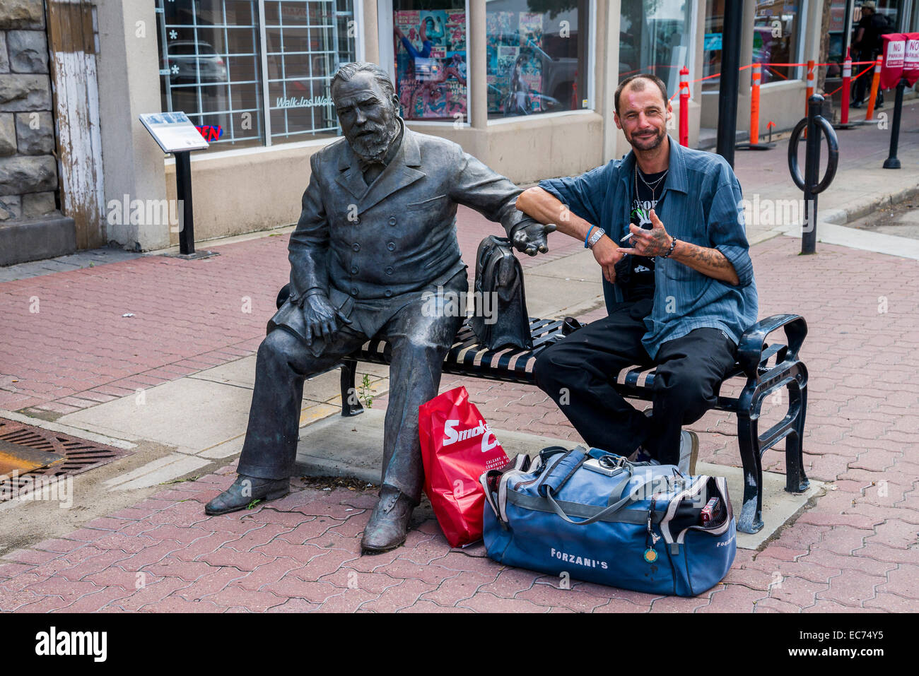 Man sitting on bench beside statue of former mayor, Reverend Gaetz, Red ...
