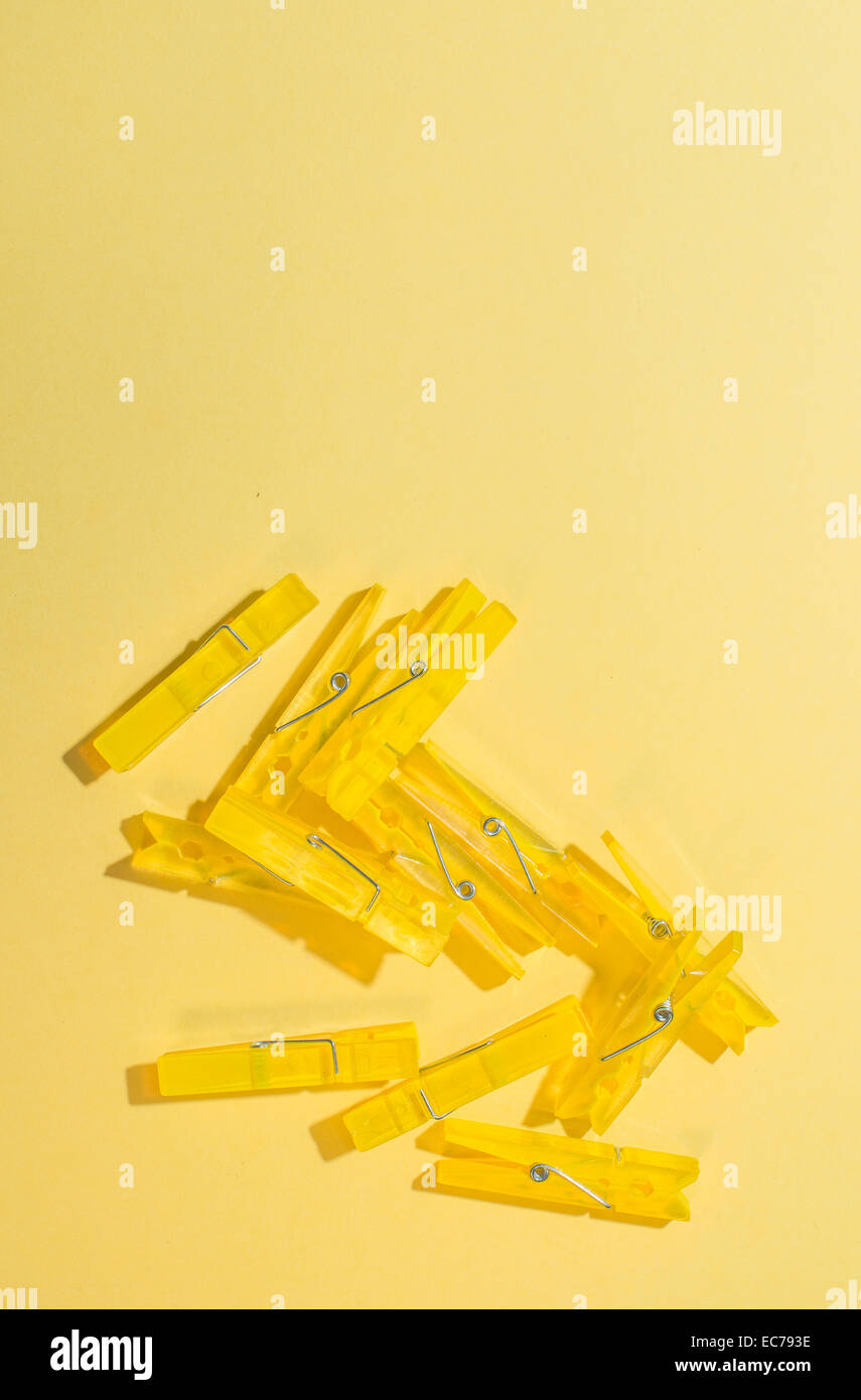 Yellow clothes pegs on paper background Stock Photo - Alamy