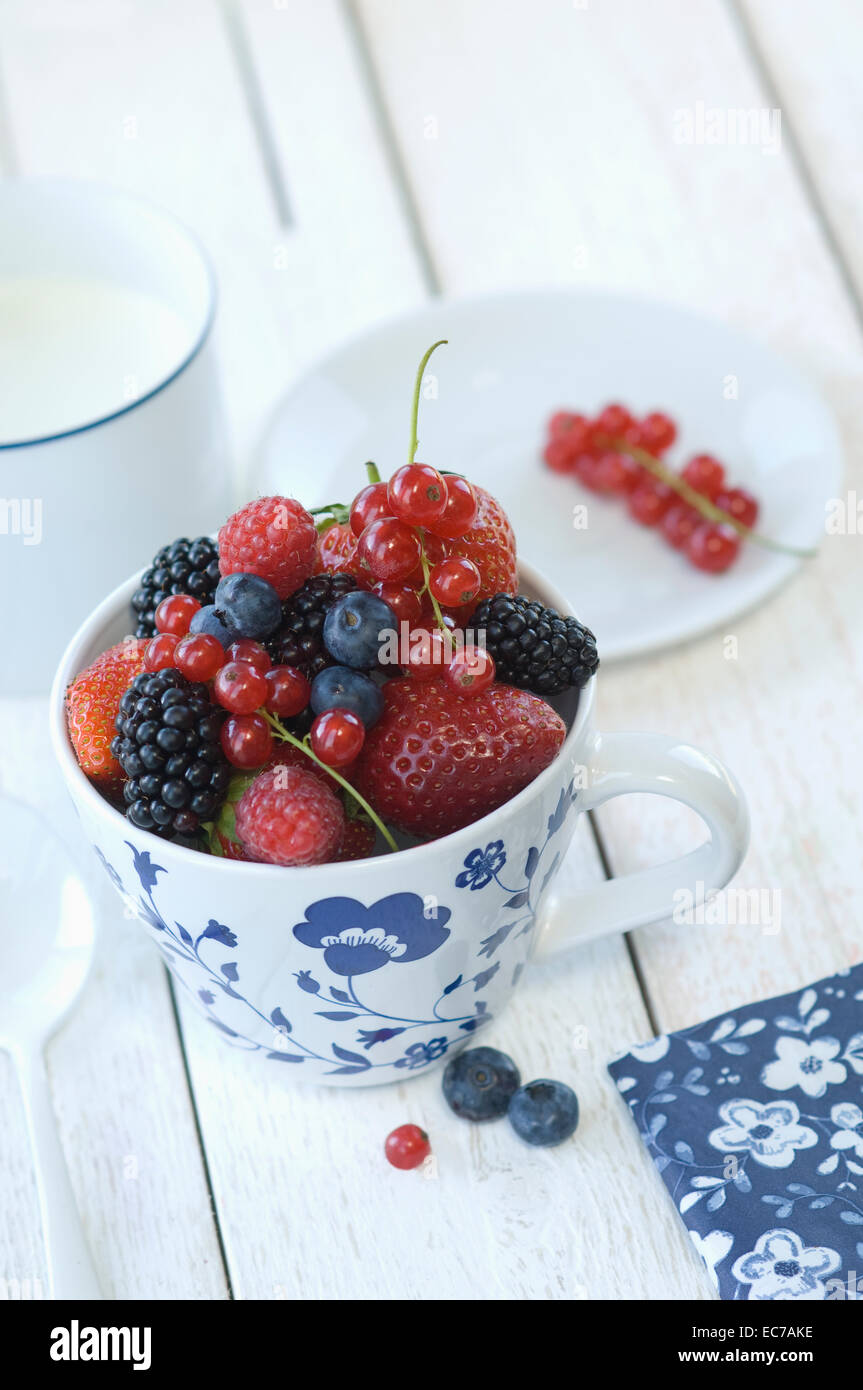 Cup of different berries on white wood Stock Photo - Alamy