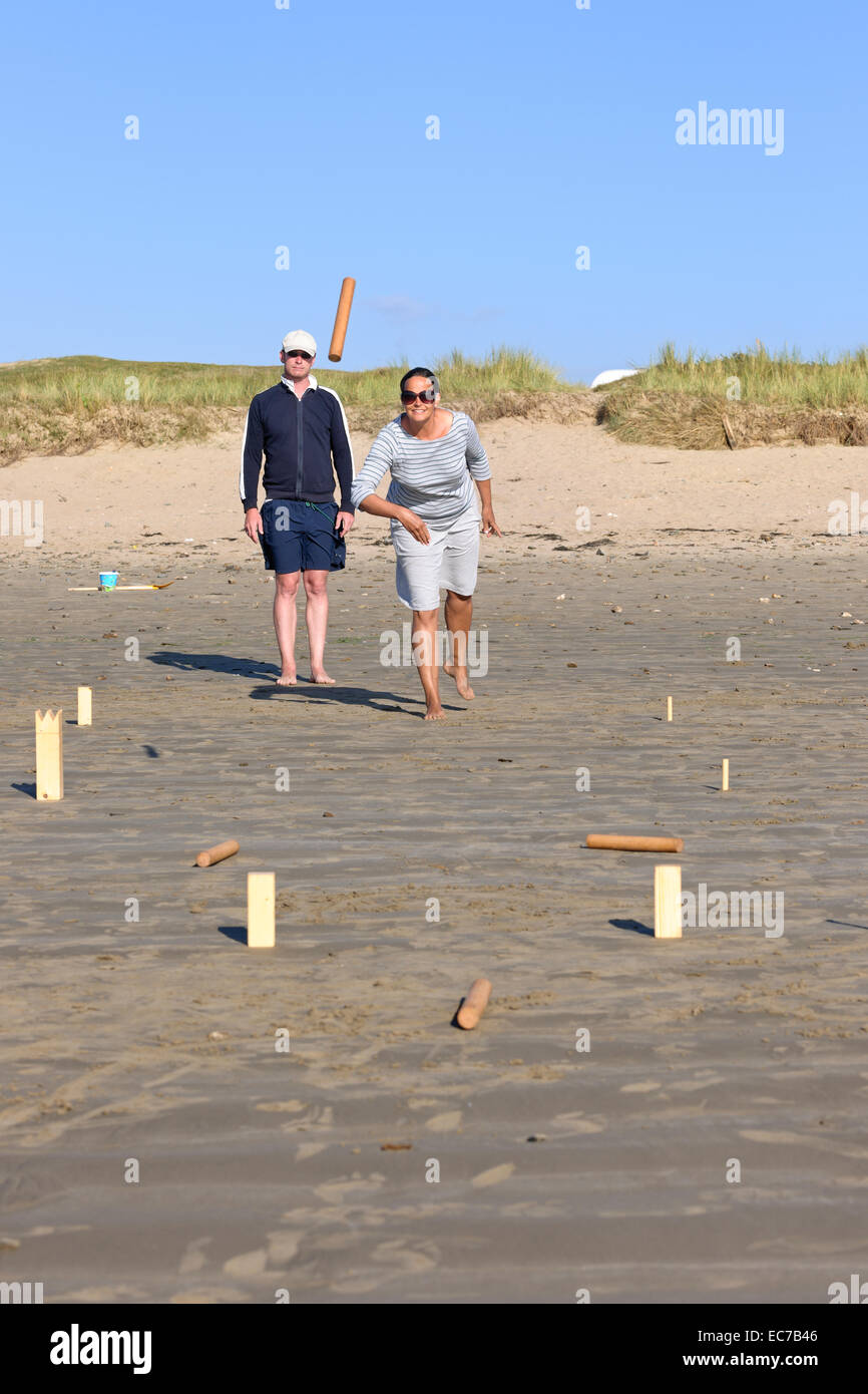 Couple playing Kubb on the beach Stock Photo - Alamy