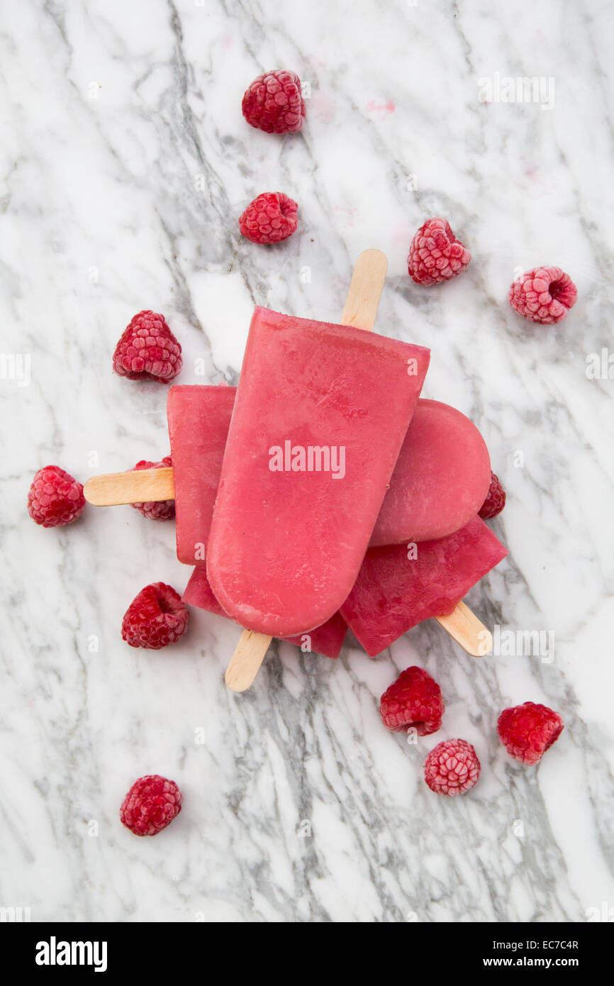 Raspberry ice lollies and frozen raspberries on marble Stock Photo - Alamy