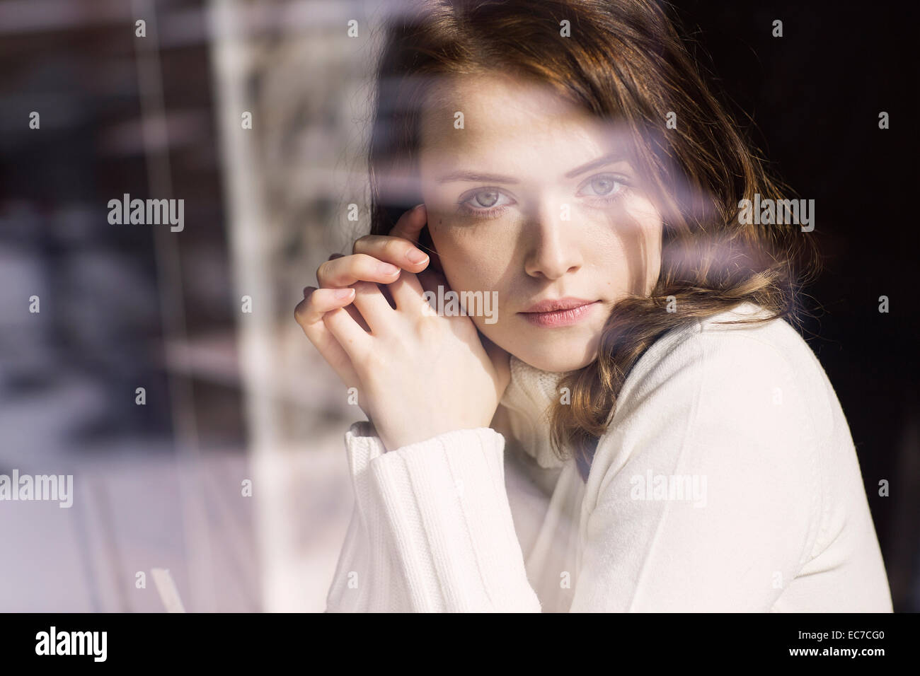 Portrait of young woman looking through window pane of a cafe Stock ...