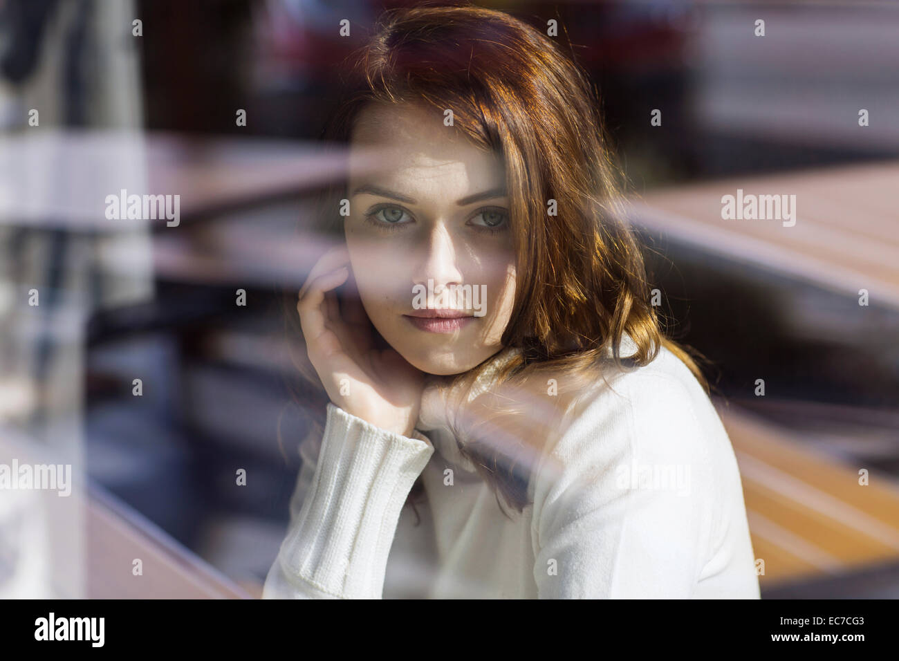 Portrait of young woman looking through window pane of a cafe Stock ...