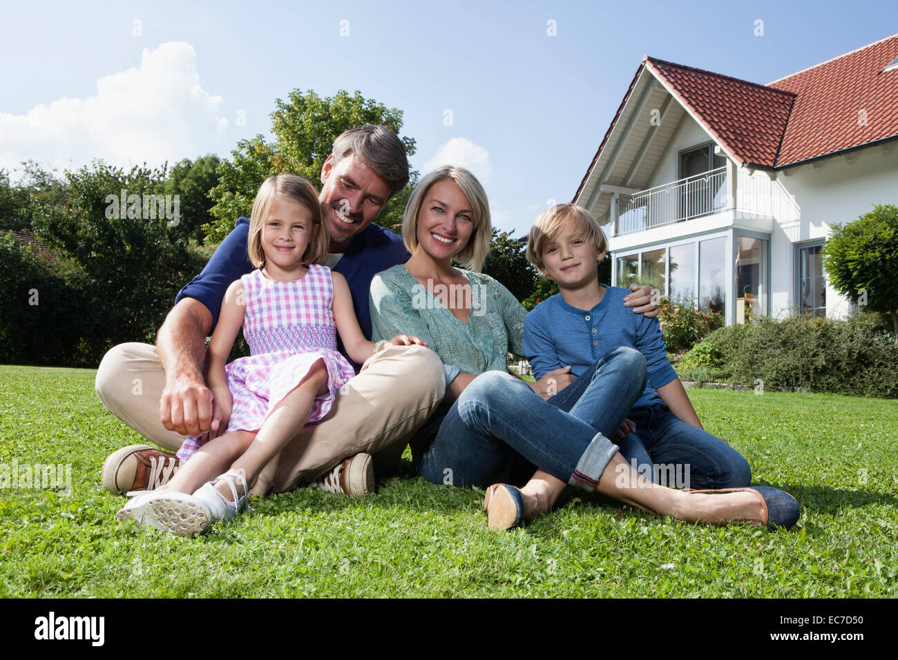 Happy family sitting on lawn in garden Stock Photo - Alamy