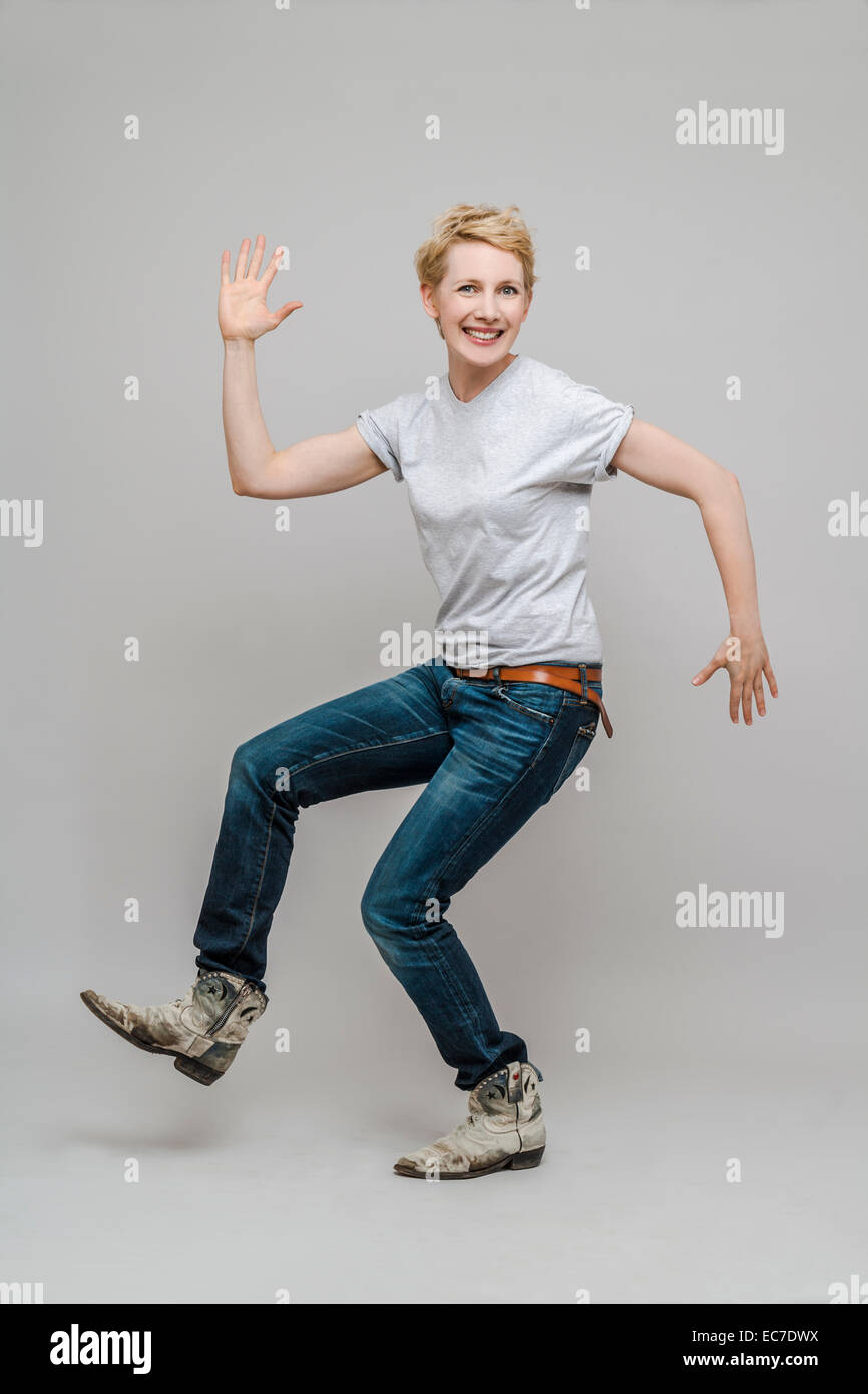 Smiling woman moving in front of grey background Stock Photo - Alamy
