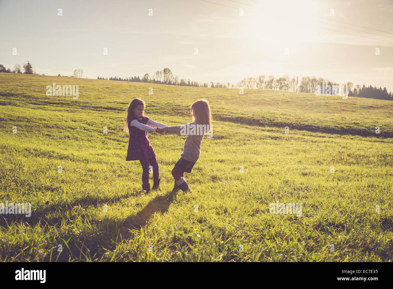 Two little girls turning around together on a meadow in backlight Stock ...