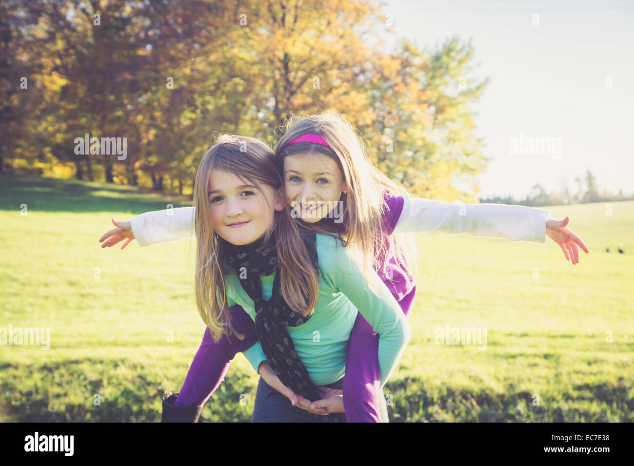 Girl giving another little girl a piggyback Stock Photo - Alamy