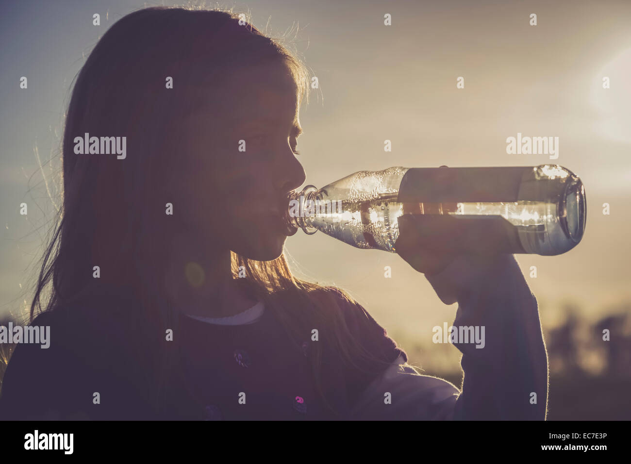 Girl drinking water out of a water bottle at backlight Stock Photo - Alamy