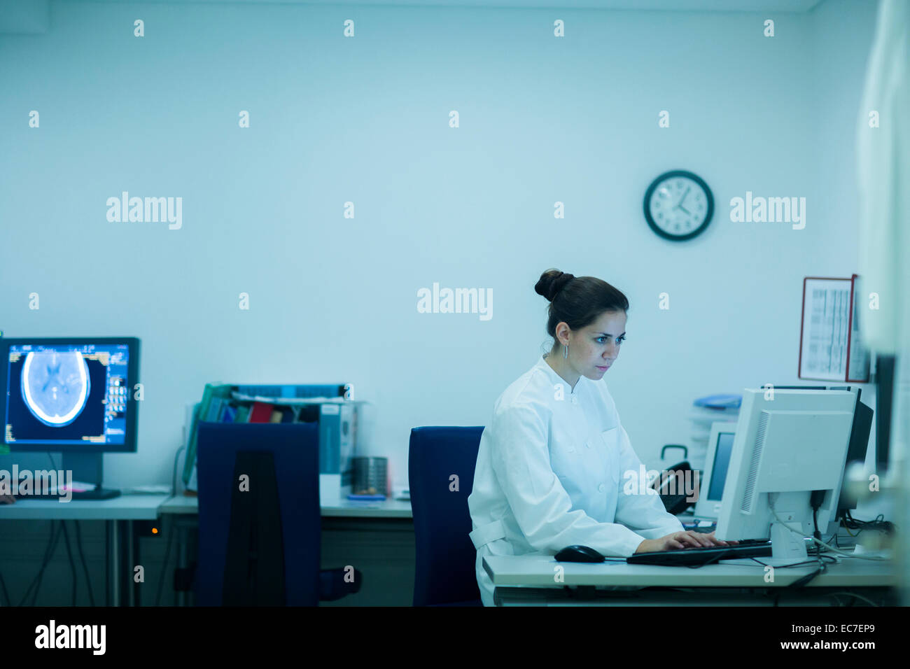 Young doctor in hospital looking at computer screen Stock Photo - Alamy