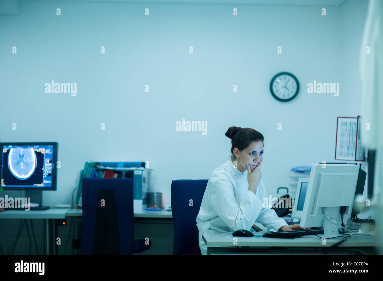 Young doctor in hospital looking at computer screen Stock Photo - Alamy