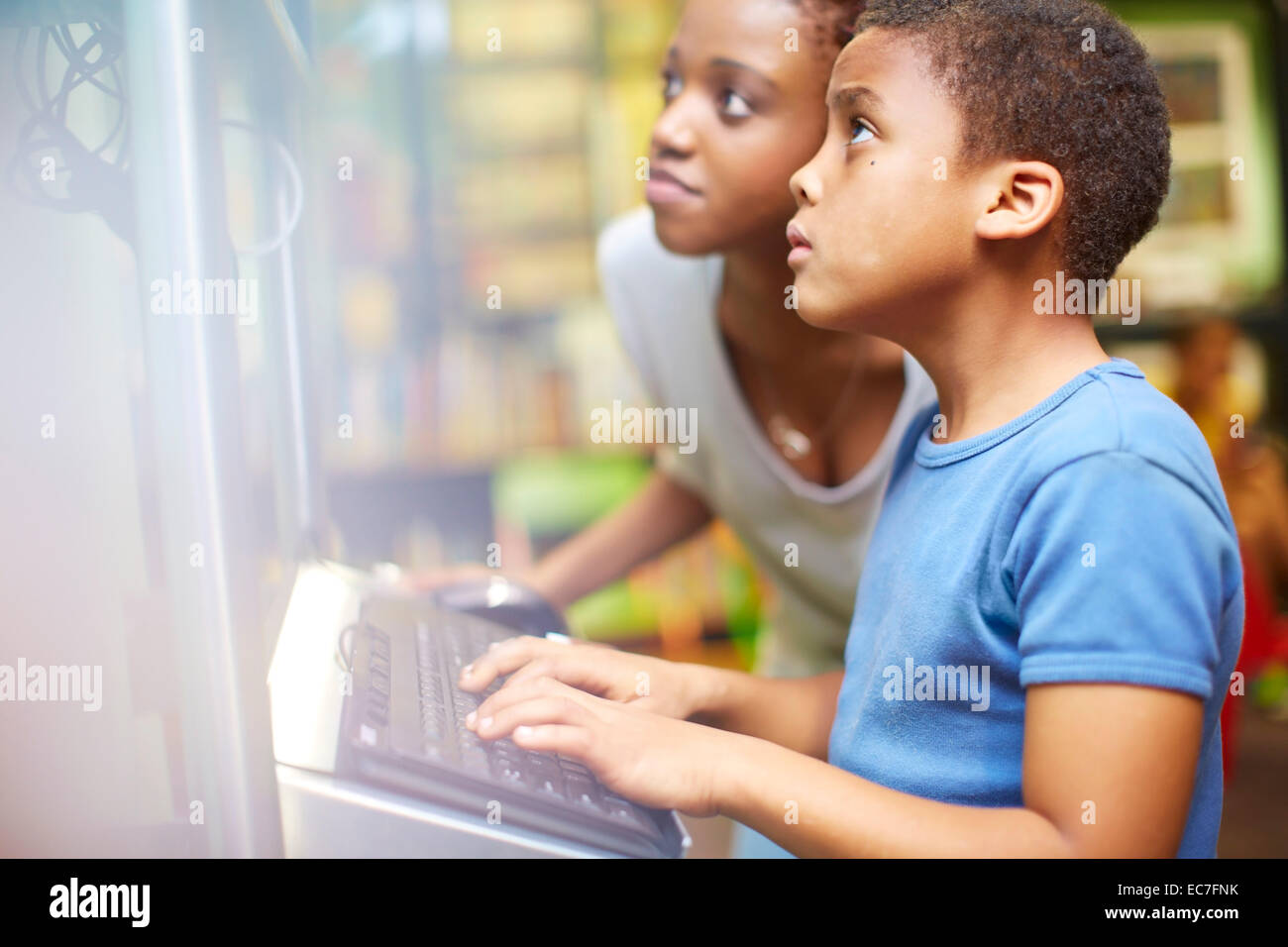 Young woman and boy using computer in library Stock Photo - Alamy