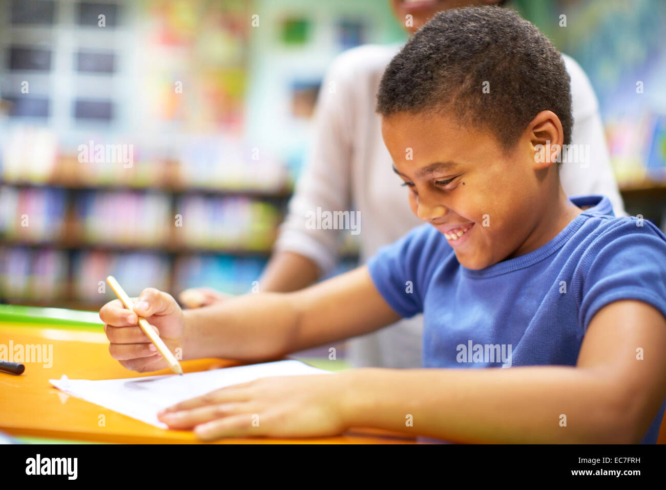 Young woman teaching boy writing on paper Stock Photo - Alamy
