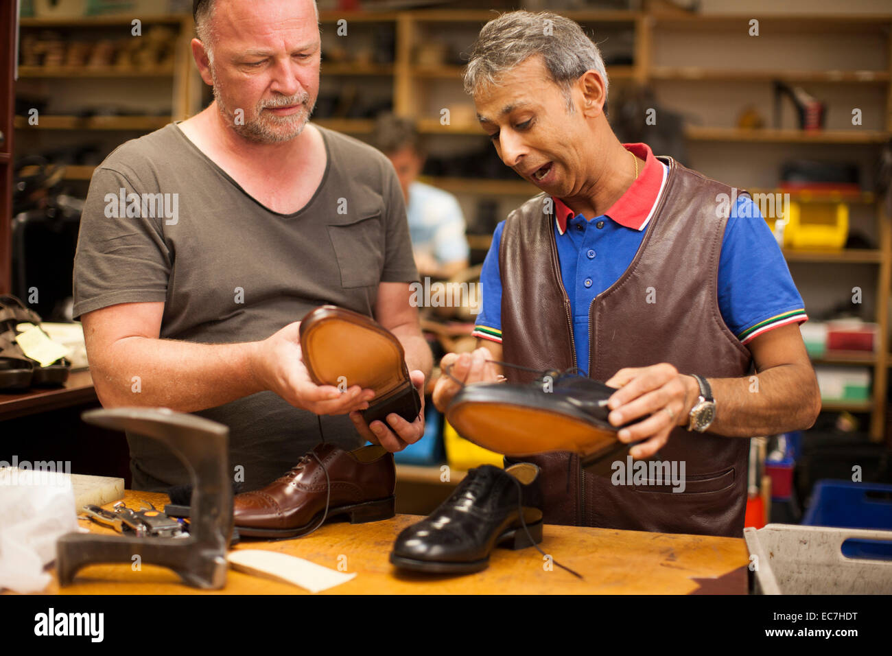 South Africa, Cape Town, cobbler explaning customer quality of his work ...