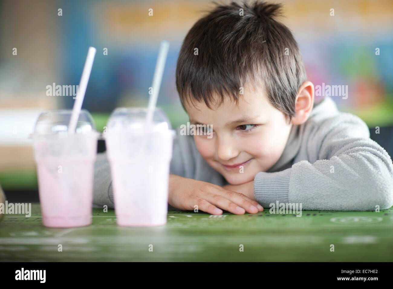 Smiling boy looking at empty milkshakecups in coffee shop Stock Photo ...