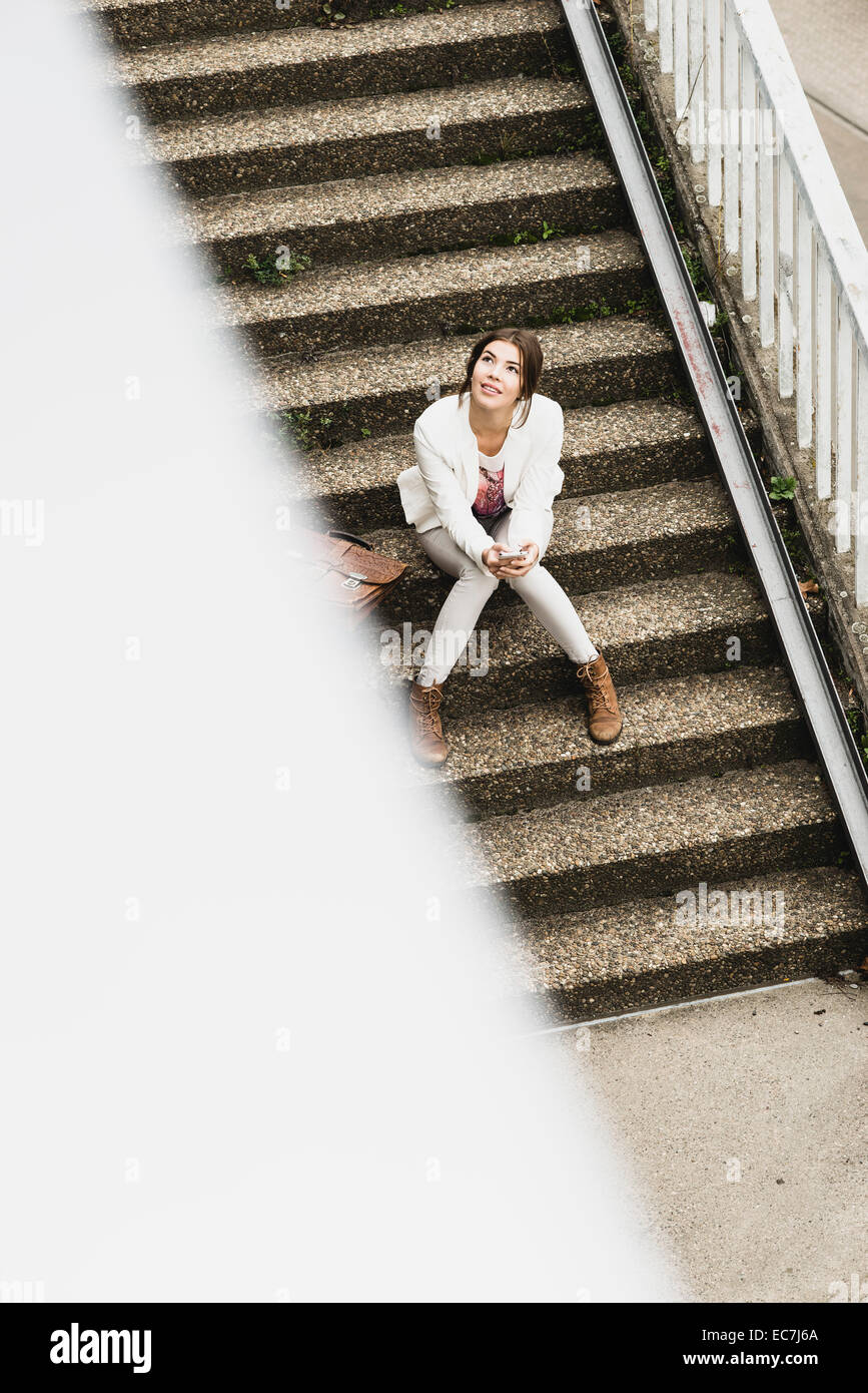 Young woman sitting on a staircase looking up, elevated view Stock ...