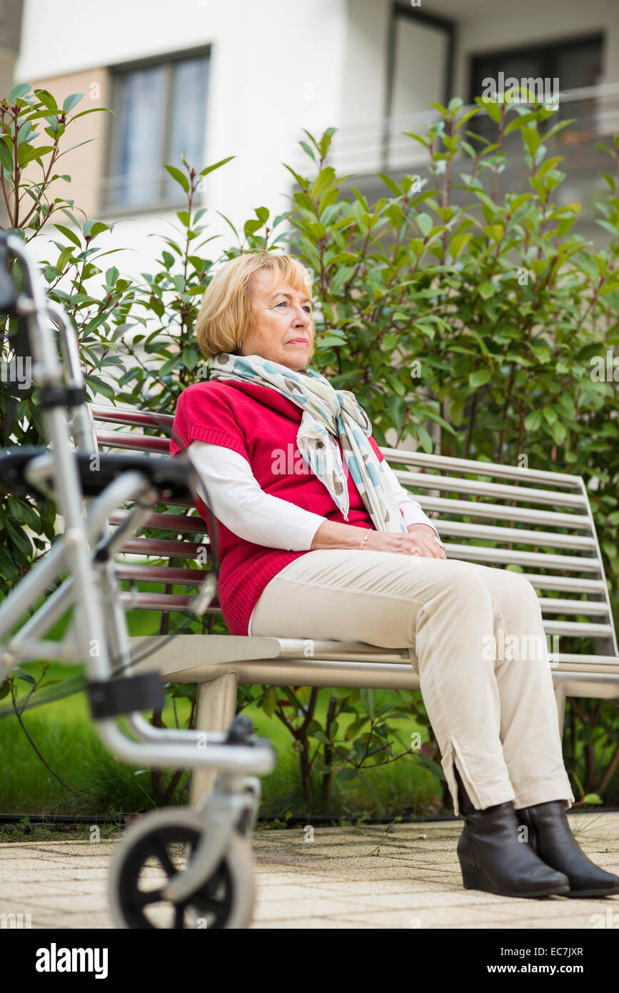Senior woman with wheeled walker sitting on a bench Stock Photo - Alamy
