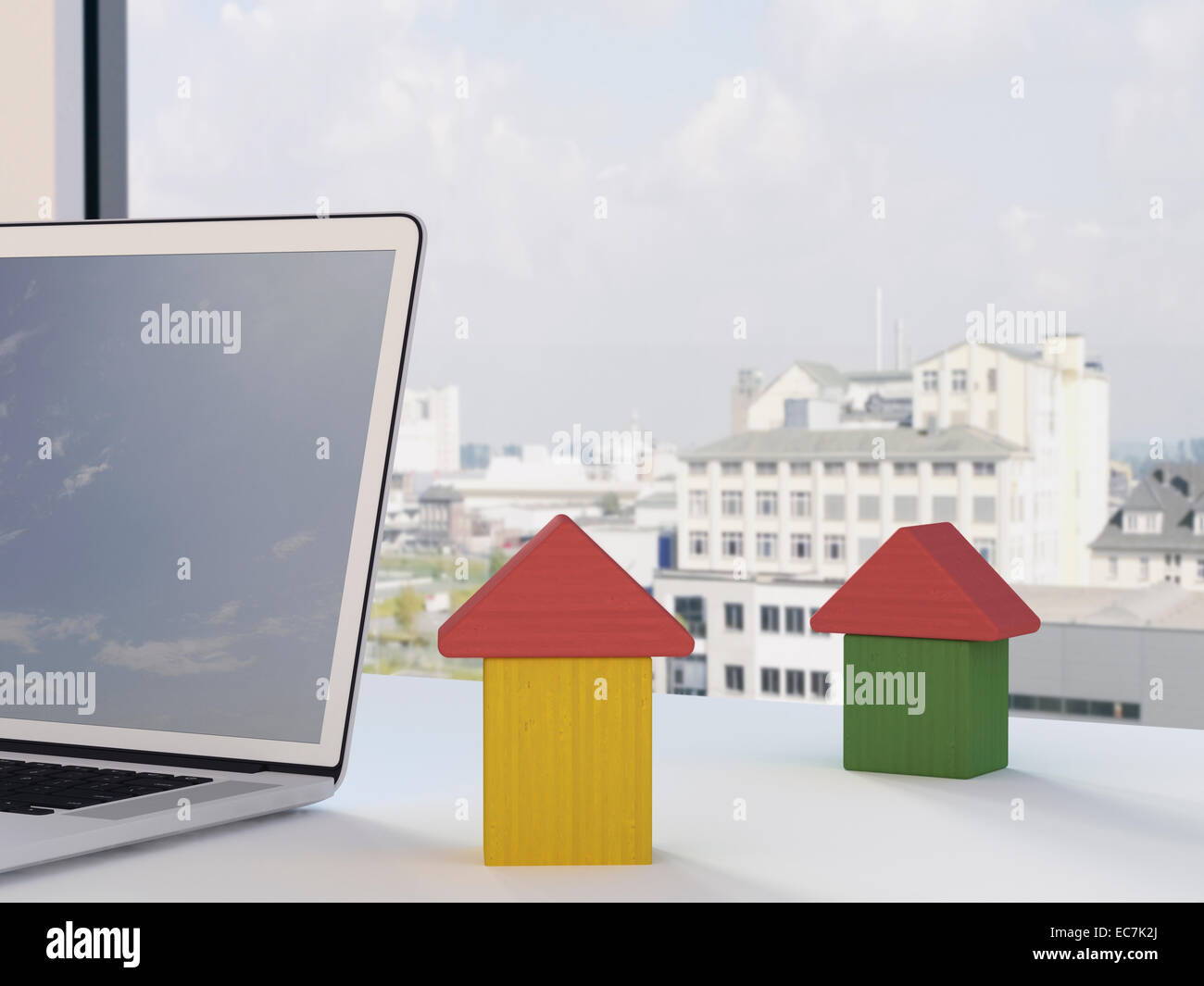 Building blocks formed like houses and laptop on desk in front of a ...