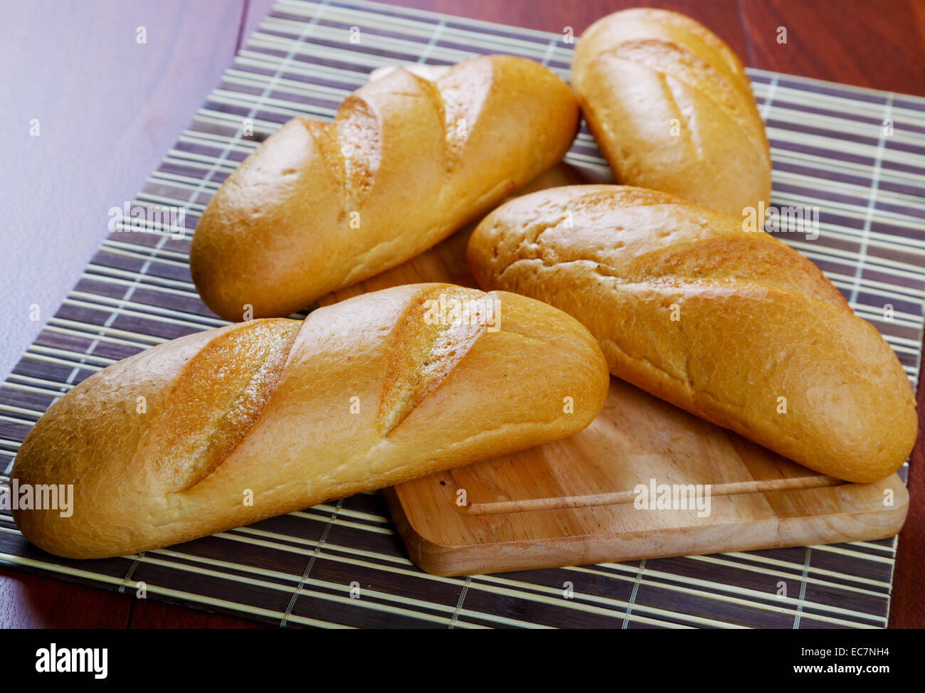 Four long loafs on a chopping board Stock Photo - Alamy