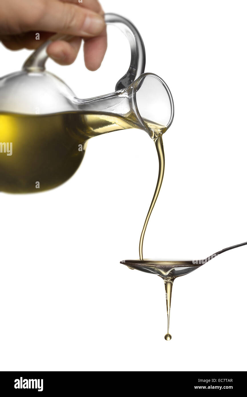 Pouring oil from jar on spoon isolated on white Stock Photo - Alamy