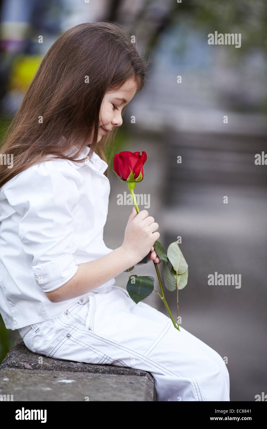 pretty girl smell rose outdoor in white suit Stock Photo - Alamy
