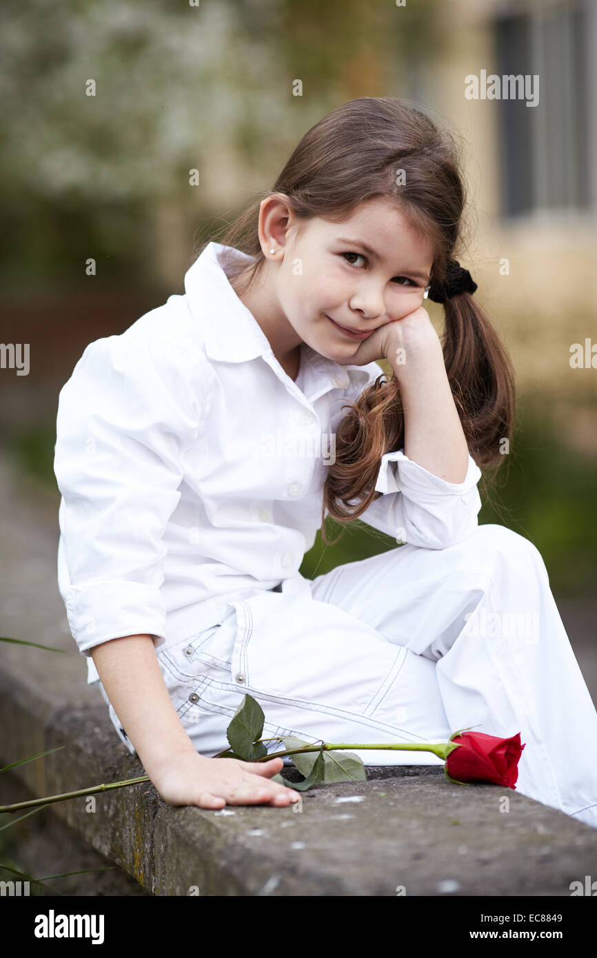 pretty girl smell rose outdoor in white suit Stock Photo - Alamy