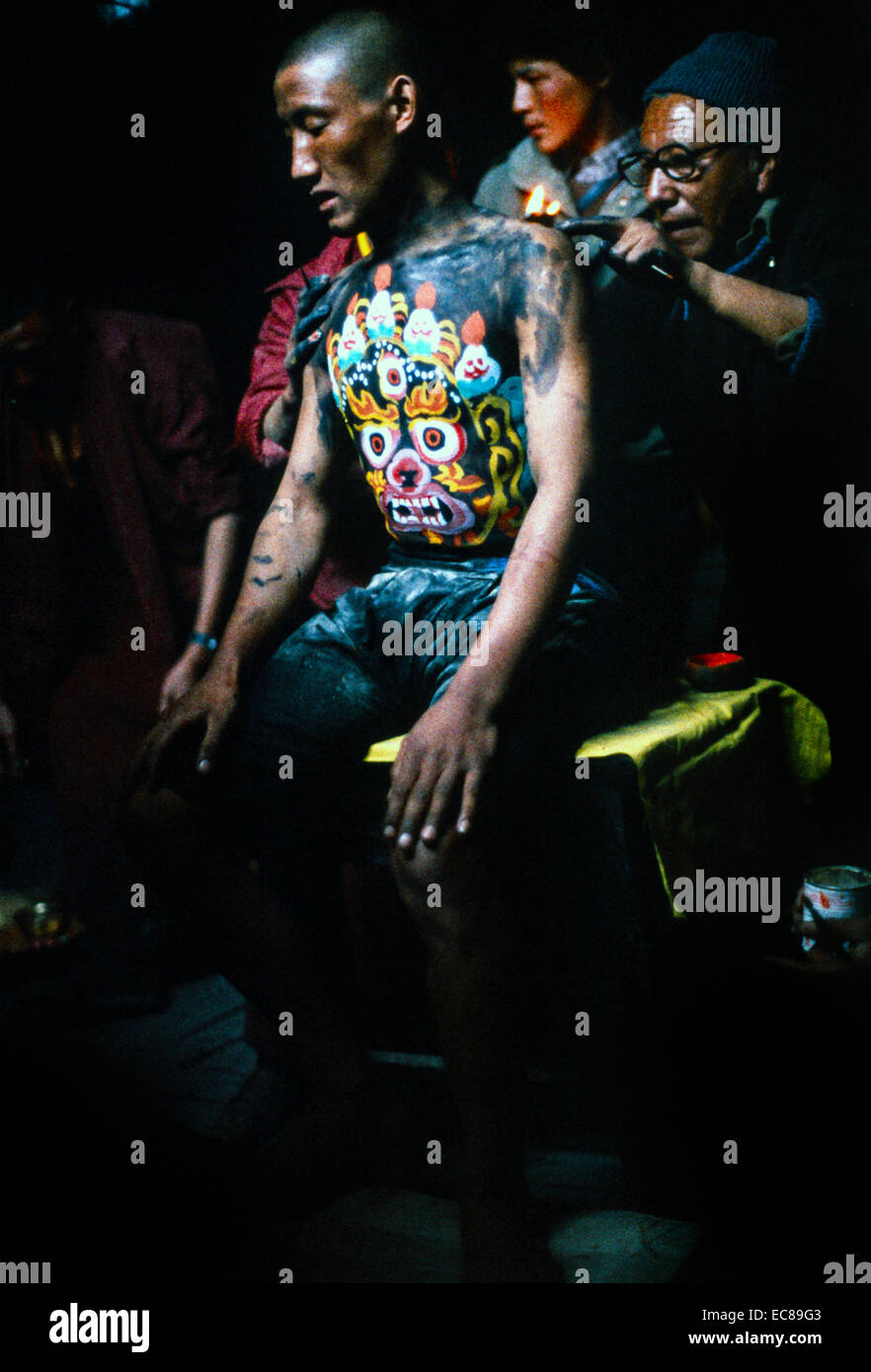 4 Matho monks preparing a young monk by painting Mahakarla - the ...