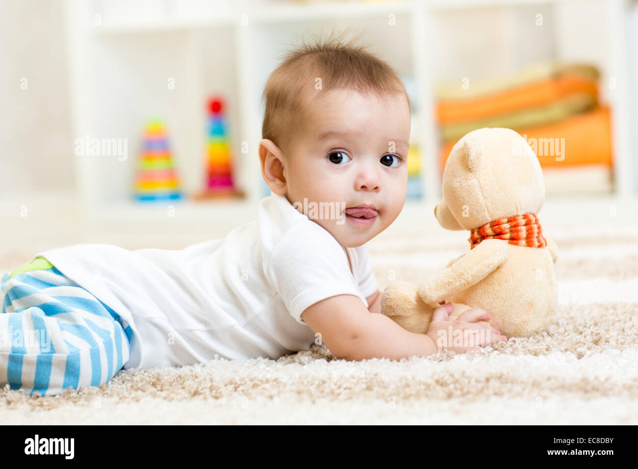 funny baby boy lying with plush toy indoor Stock Photo - Alamy